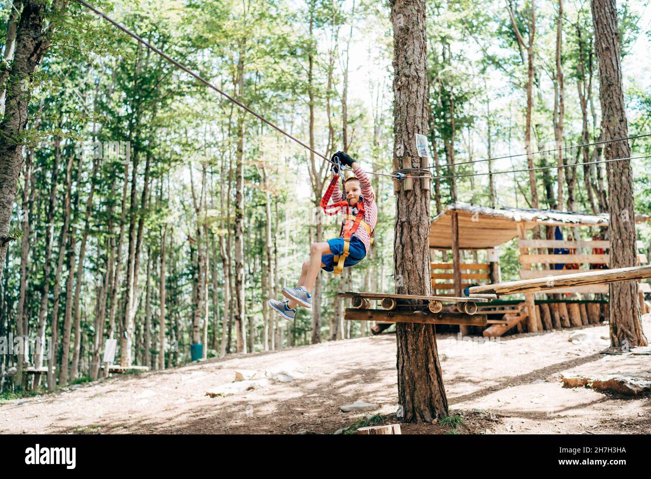 Boy goes down the zip line holding on to the insurance with his hands ...
