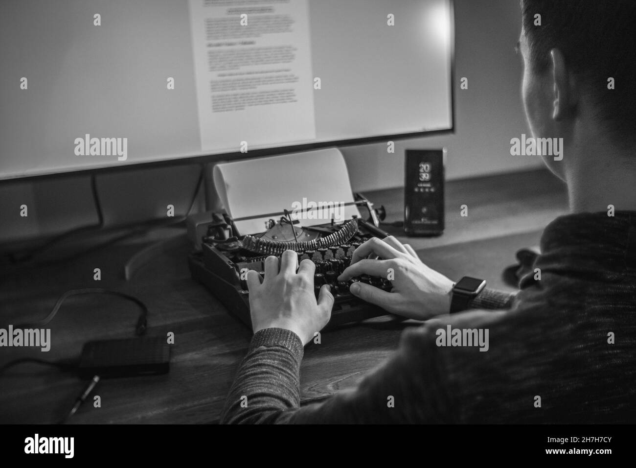Grayscale shot of a Caucasian man typing on a typewriter Stock Photo ...