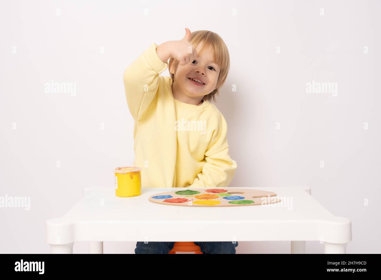 Inspired little boy at the table drawing with thumb up isolated on ...