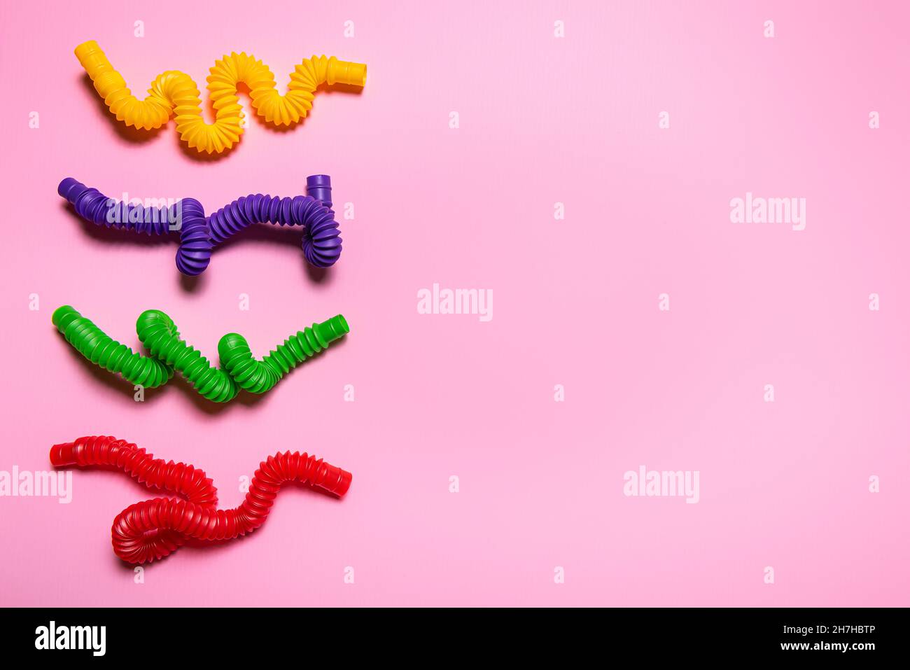 Four colorful red, purple, green and yellow pop tube children toys bent ...
