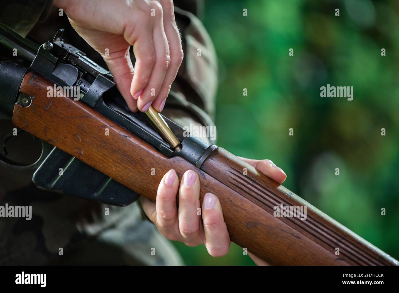 A lady soldier inserts a cartridge into the chamber of a self-reloading ...