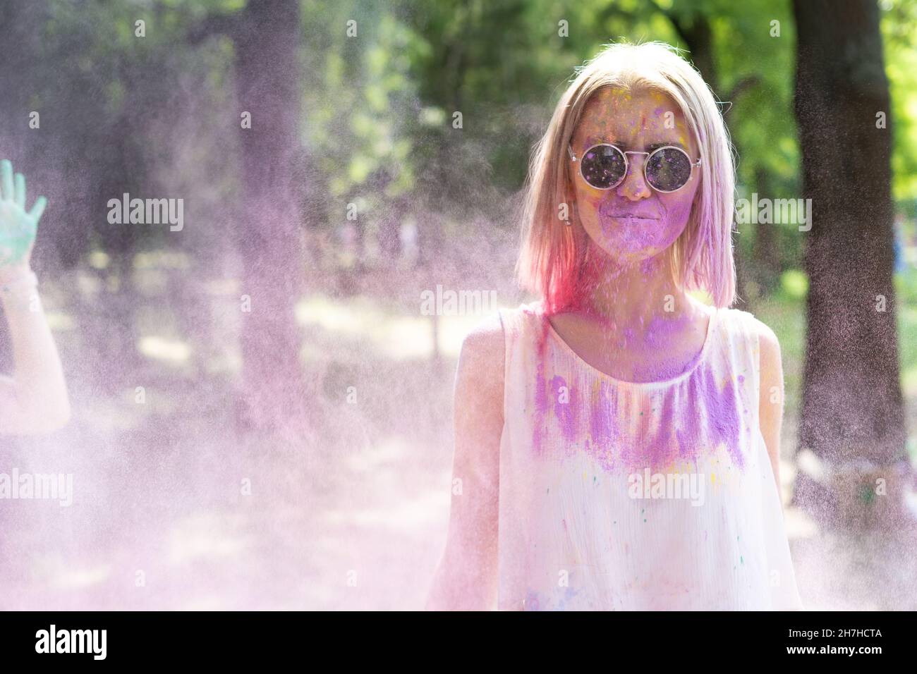 young woman with dry color powder of holi paints explodes around her ...