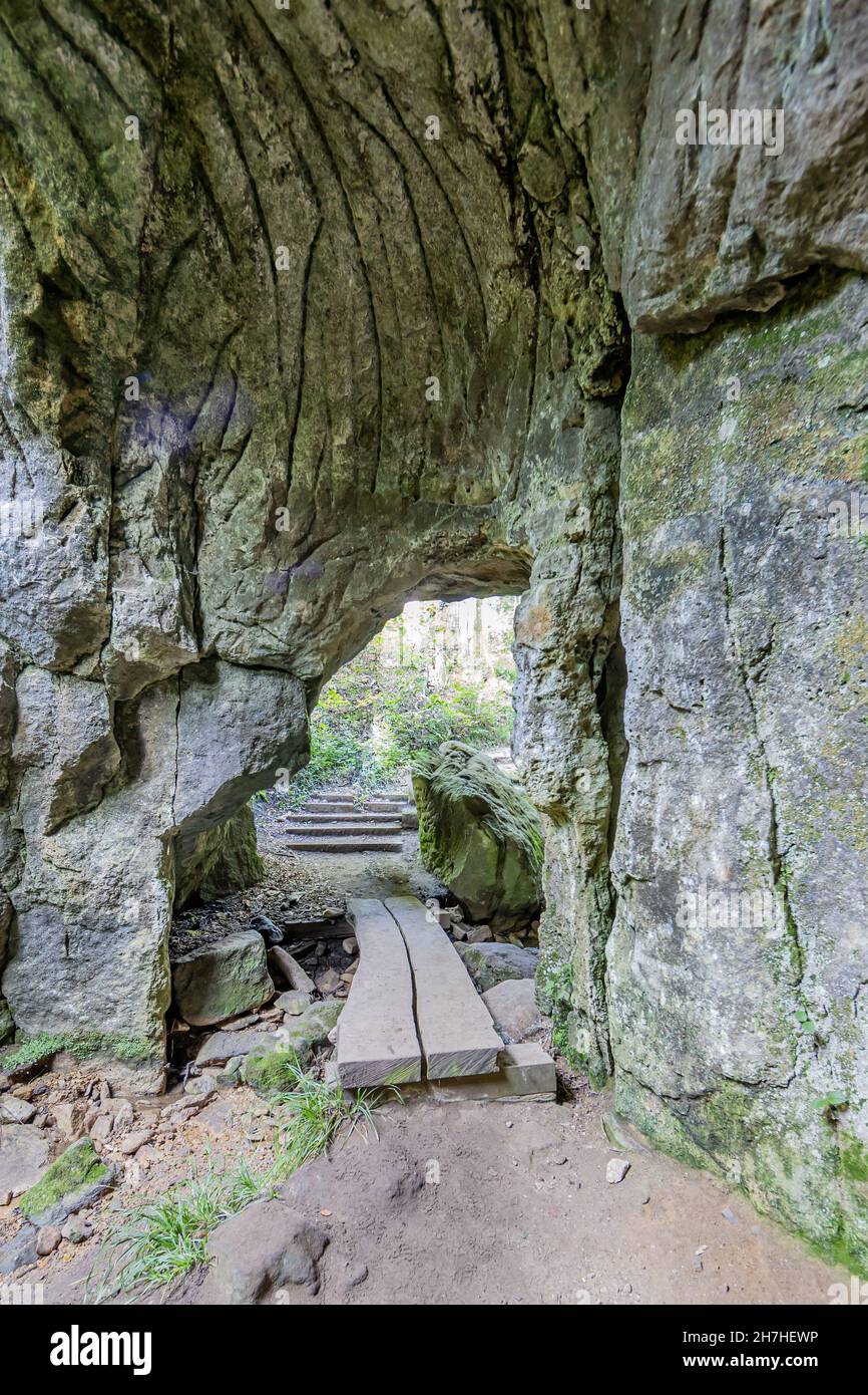 Footpath crossing a tunnel in a huge rock formation with wooden planks ...