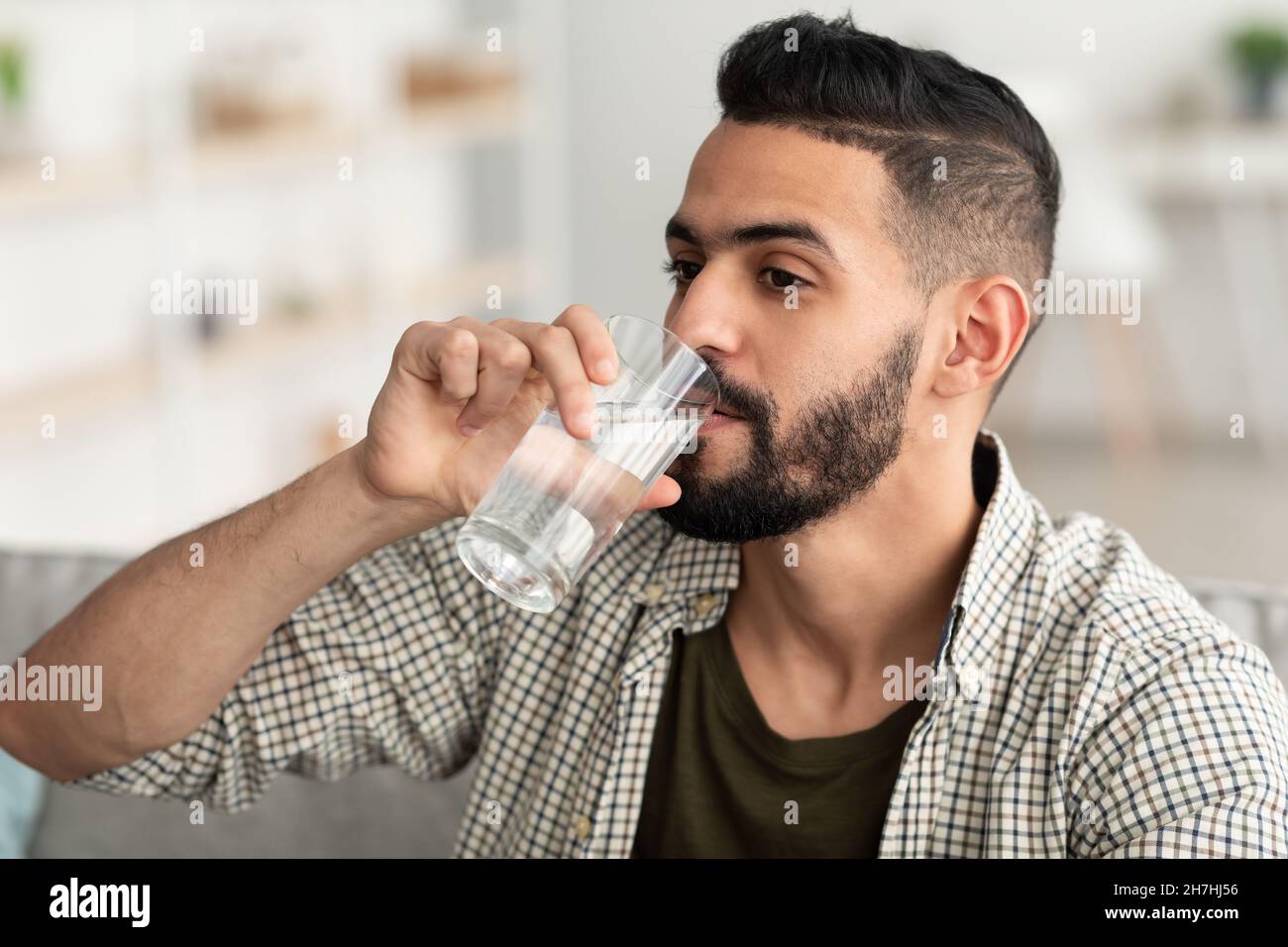 Healthy lifestyle concept. Millennial Arab guy drinking water from ...