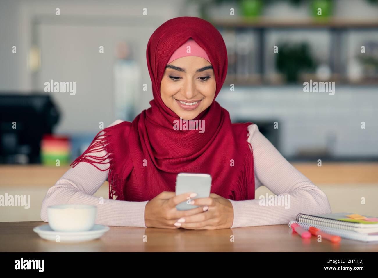Cheerful muslim lady SMM-manager using mobile phone at cafe Stock Photo ...
