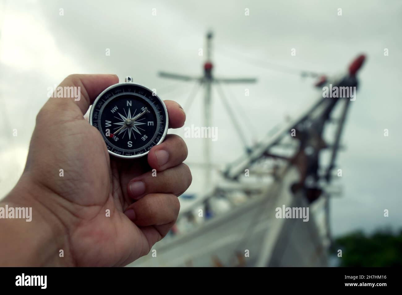 Hand held navigation compass with wooden ship blur background outdoor ...