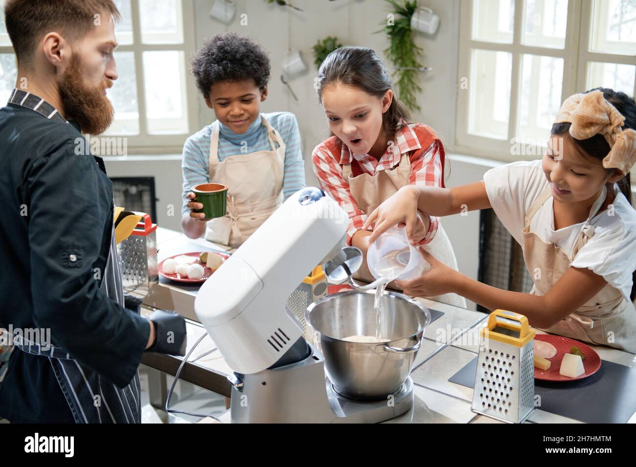 Group of happy children cooking together with cook in the kitchen, they ...