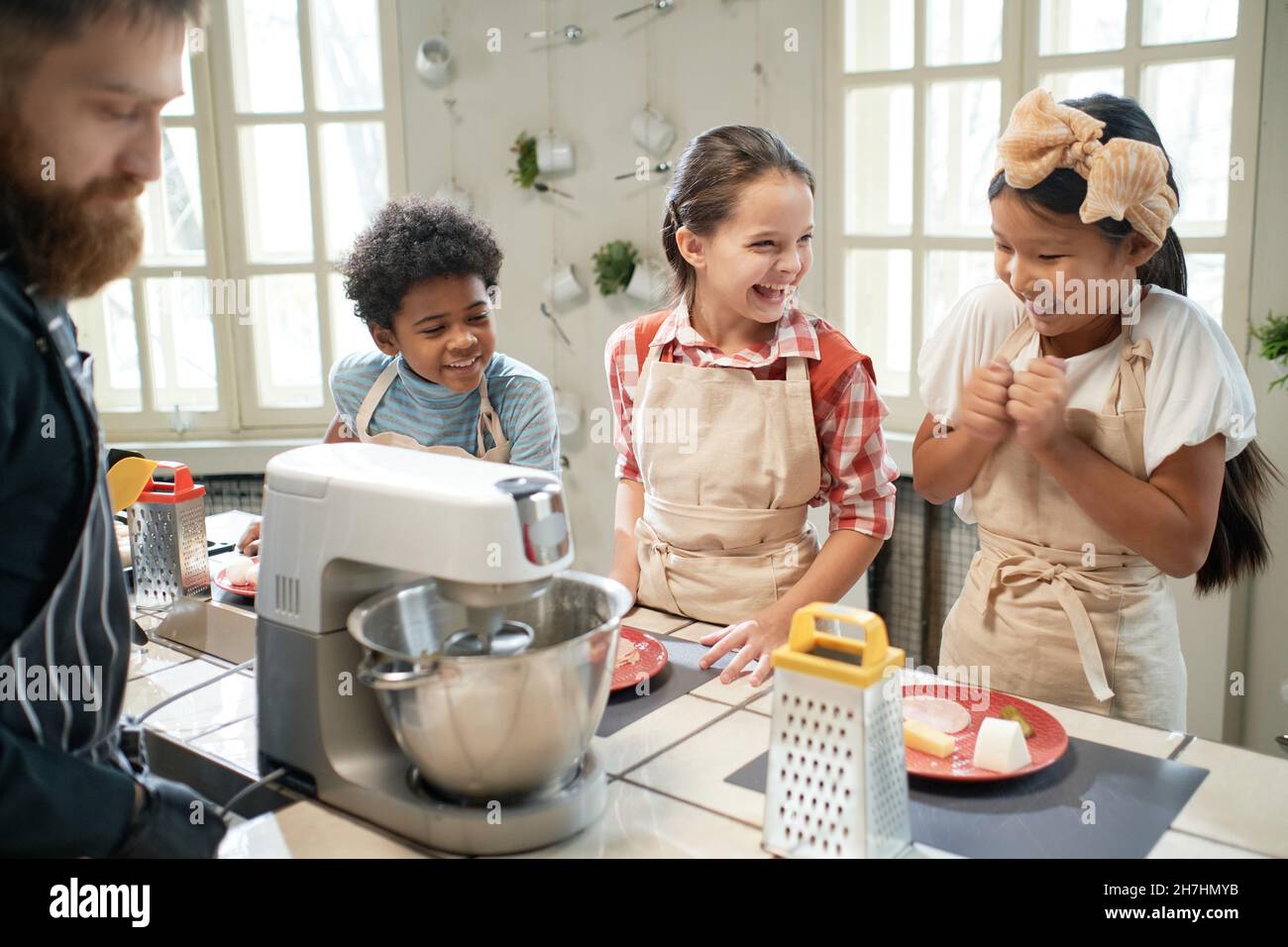 Group of happy children laughing during cooking lesson with cook in the ...