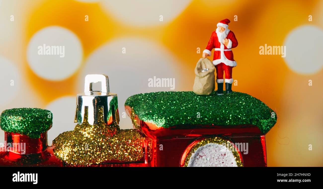 a miniature santa carrying a sack with gifts standing on a toy train ...