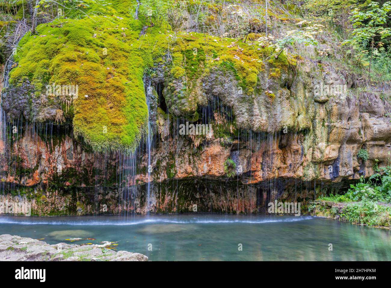 Moss covered sandstone rock formation with crystalline calcareous water ...