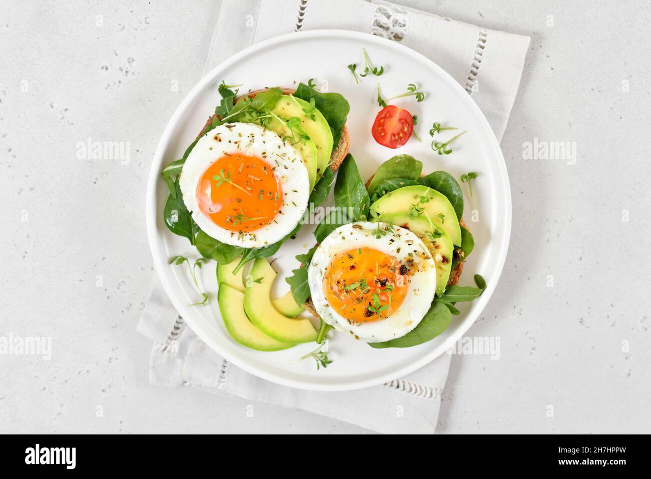Bread with fried eggs, avocado and greens. Healthy breakfast. Top view ...