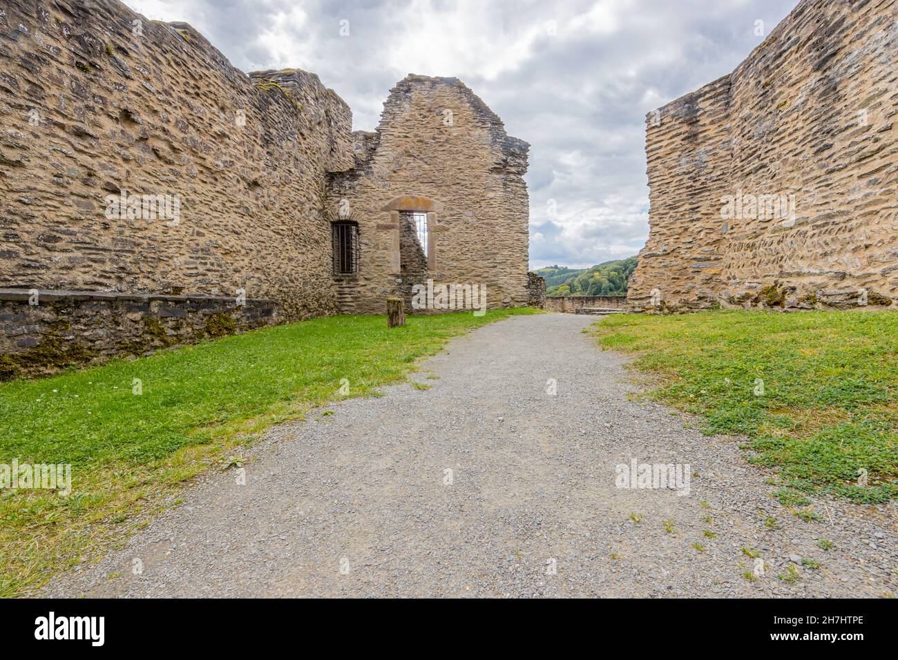 Dirt path between green grass and deteriorated stone walls in the ...