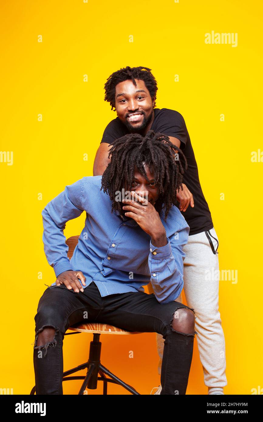 two african american guys posing cheerful together on yellow background ...