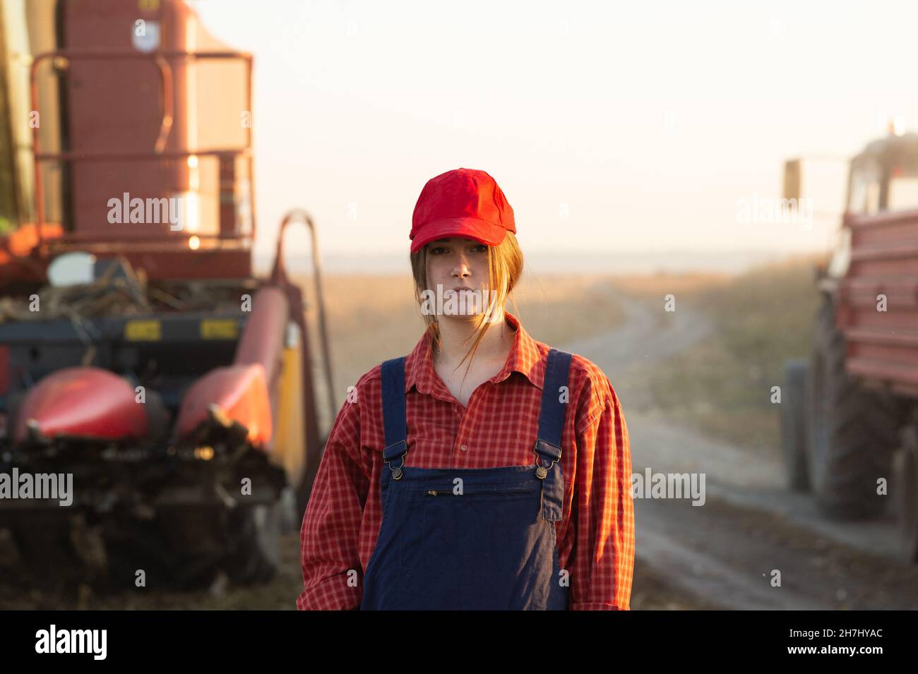 Young farmer girl in the corn field. Agricultural machinery in ...