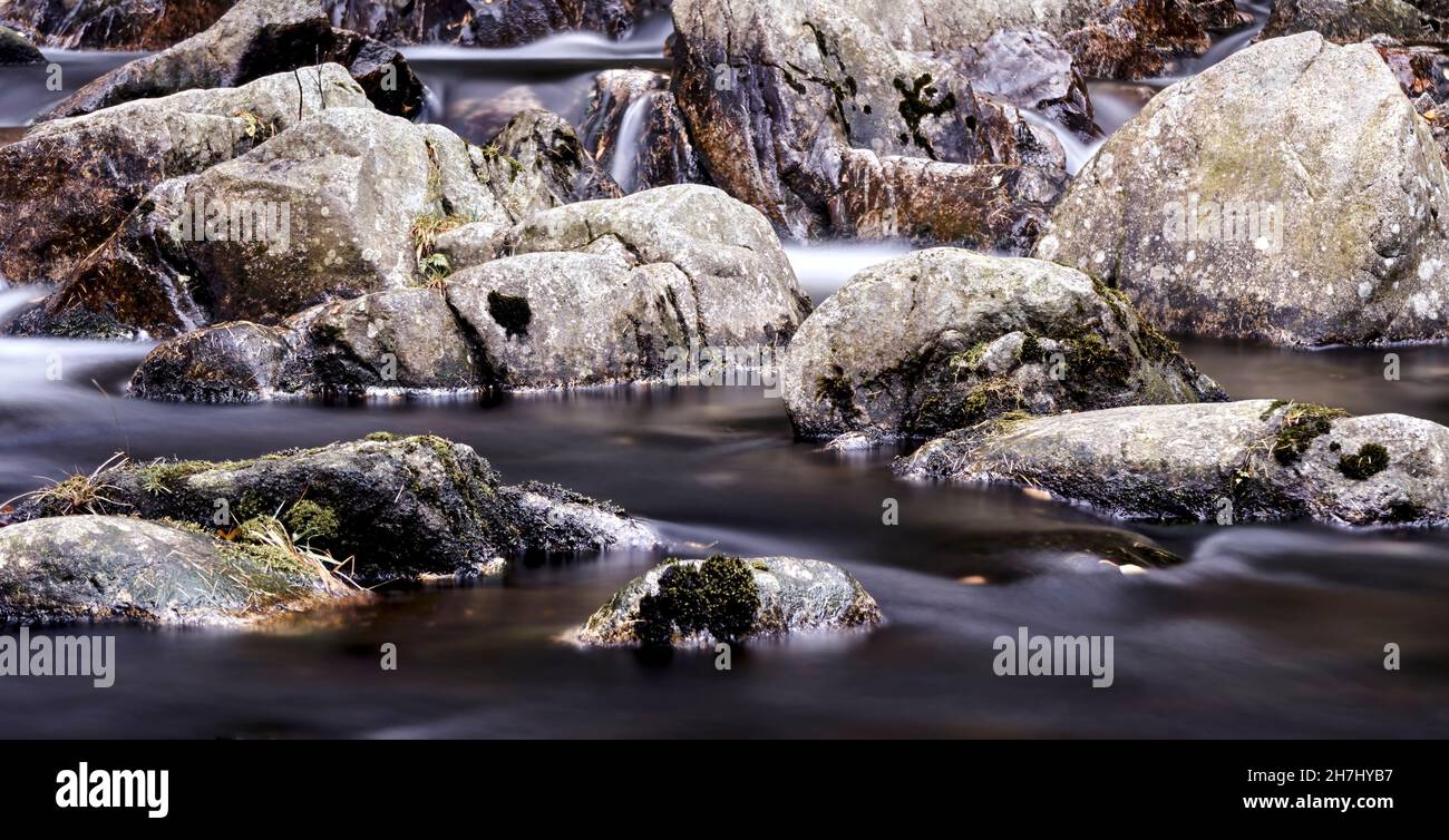 Rounded granite rocks in stream bed with velvet exposed water surface ...