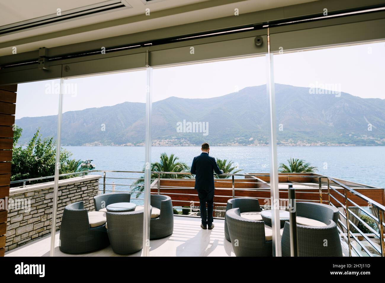 Man stands on the terrace of a luxury hotel and looks out to the sea ...