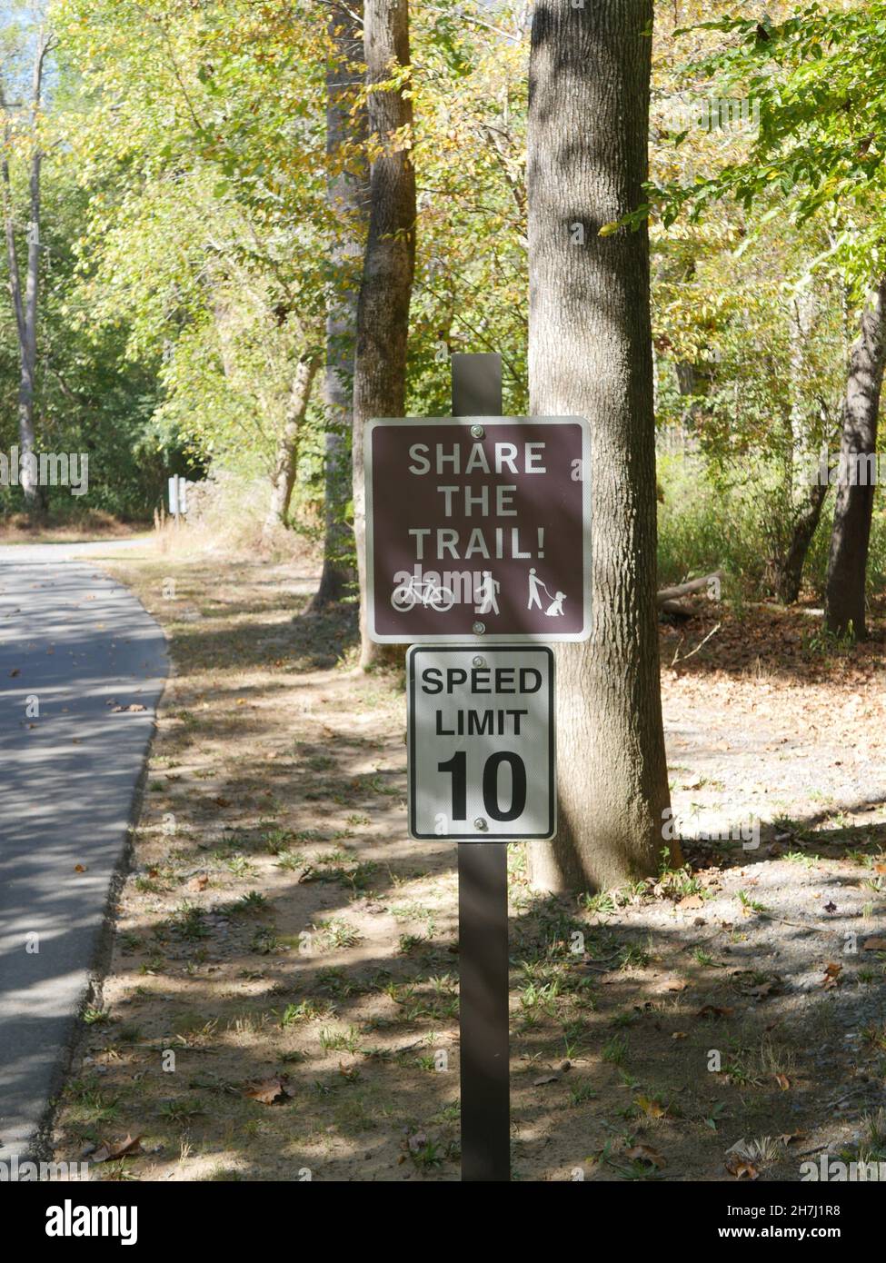 Vertical shot of a 'share the trail' and 'speed limit' signs by the ...