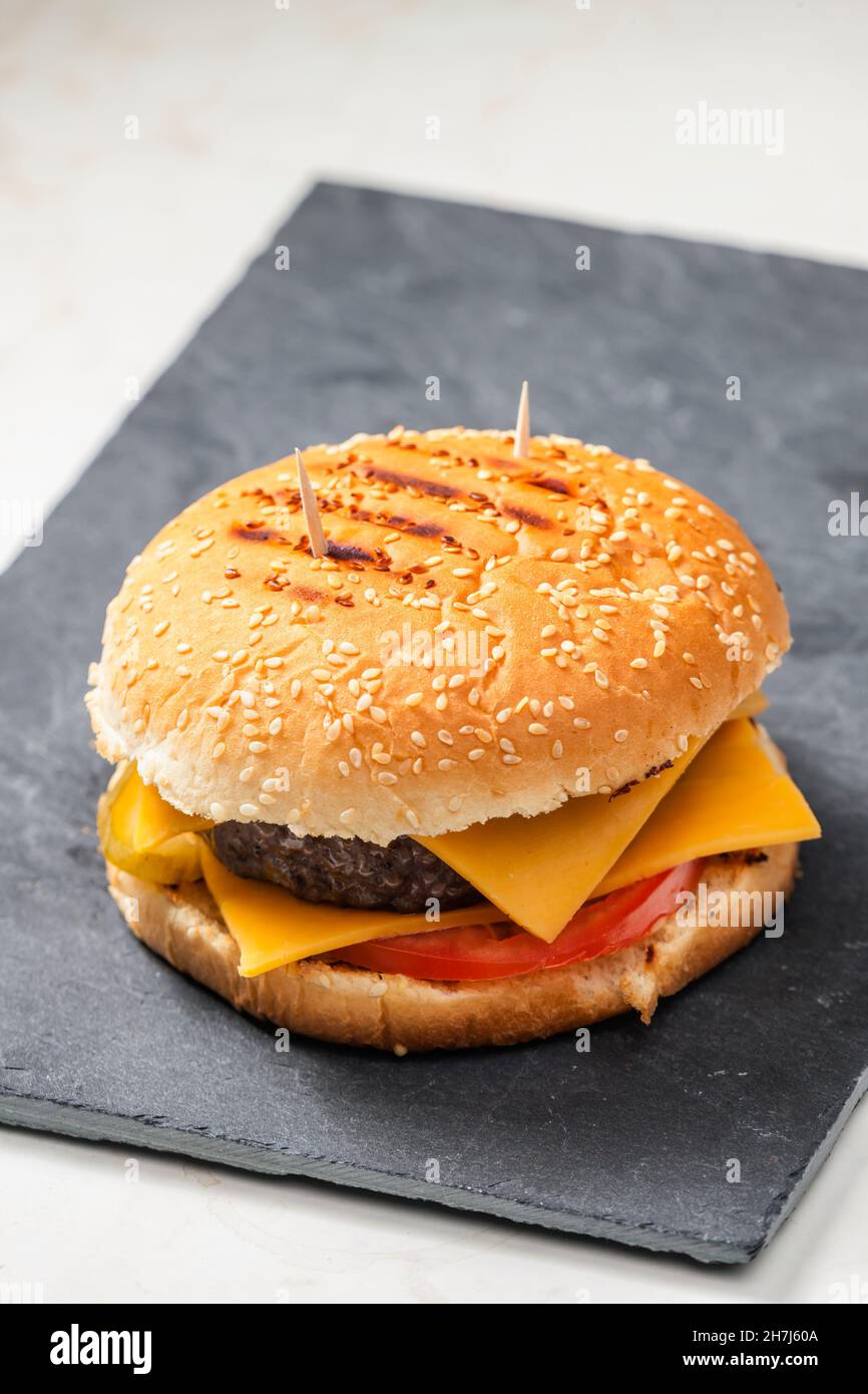 still life of cheeseburger on black plate Stock Photo - Alamy