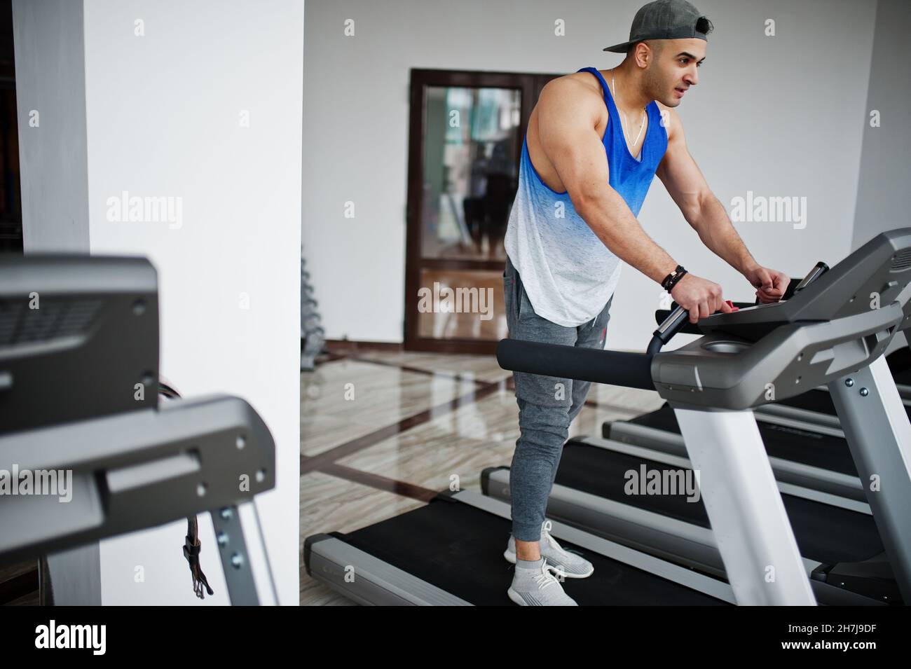 Fit and muscular arabian man running on treadmill in gym Stock Photo ...