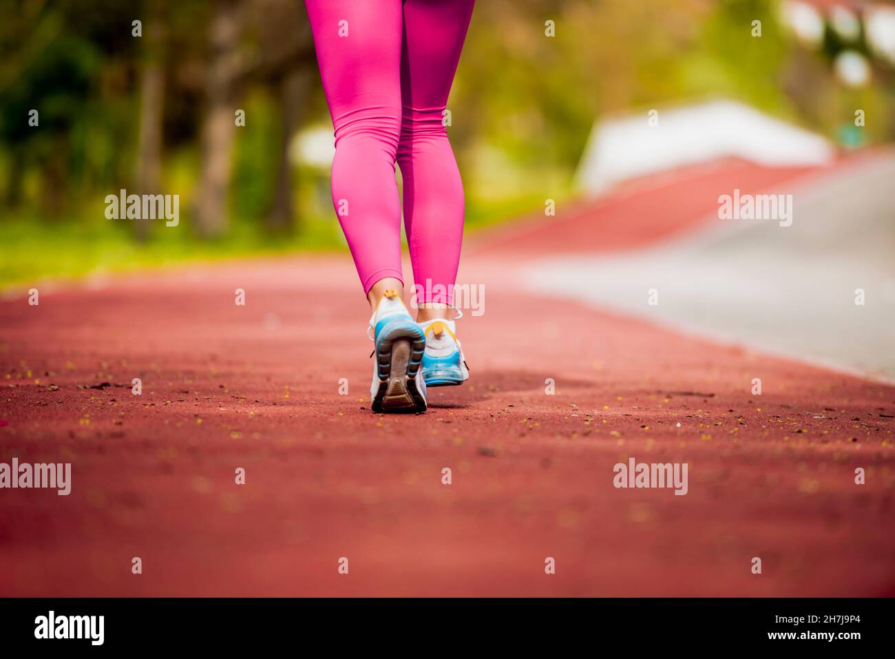 Feet of an athlete running on a park pathway training for fitness and ...