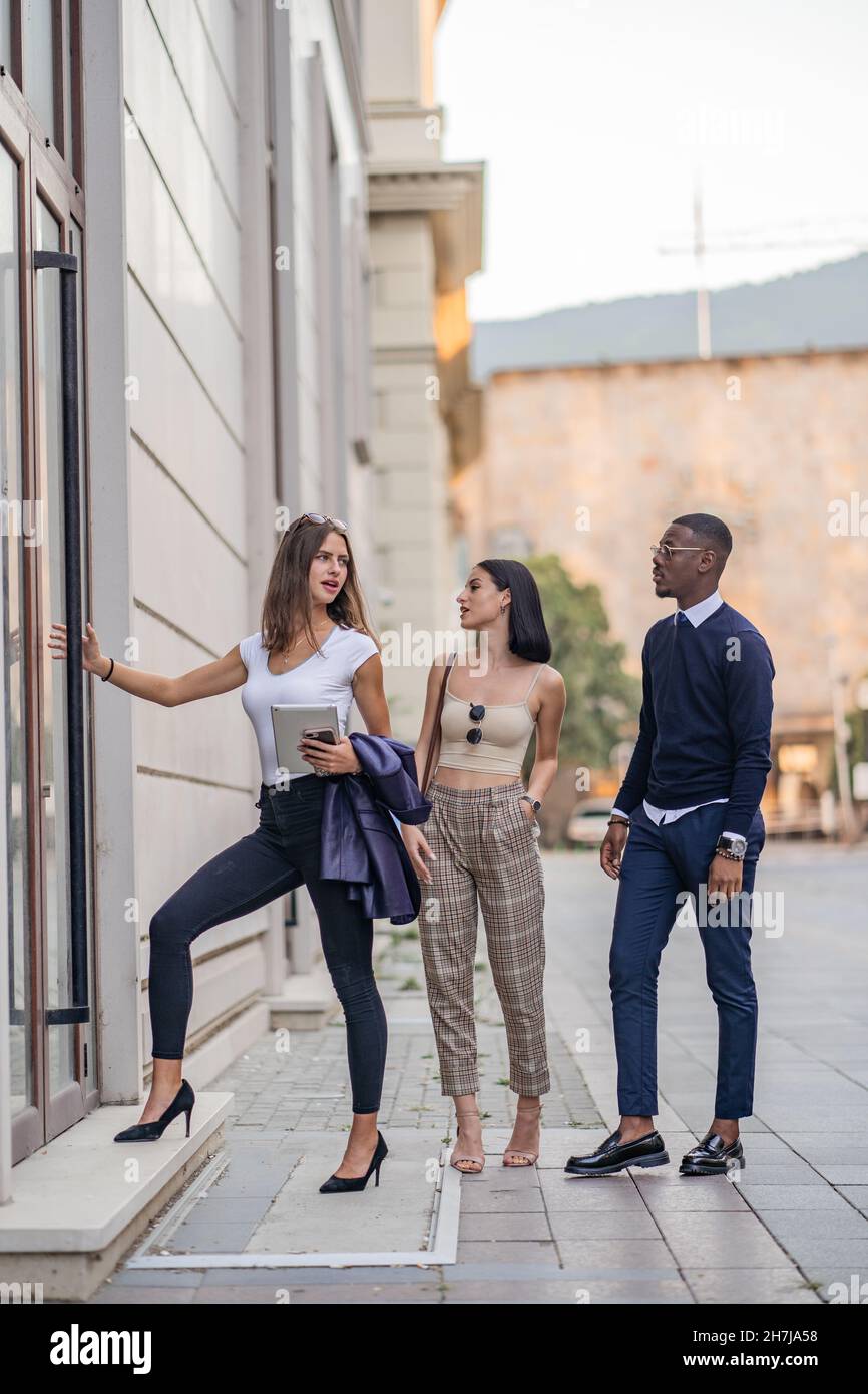 Three multiracial business co workers are standing in front of the ...