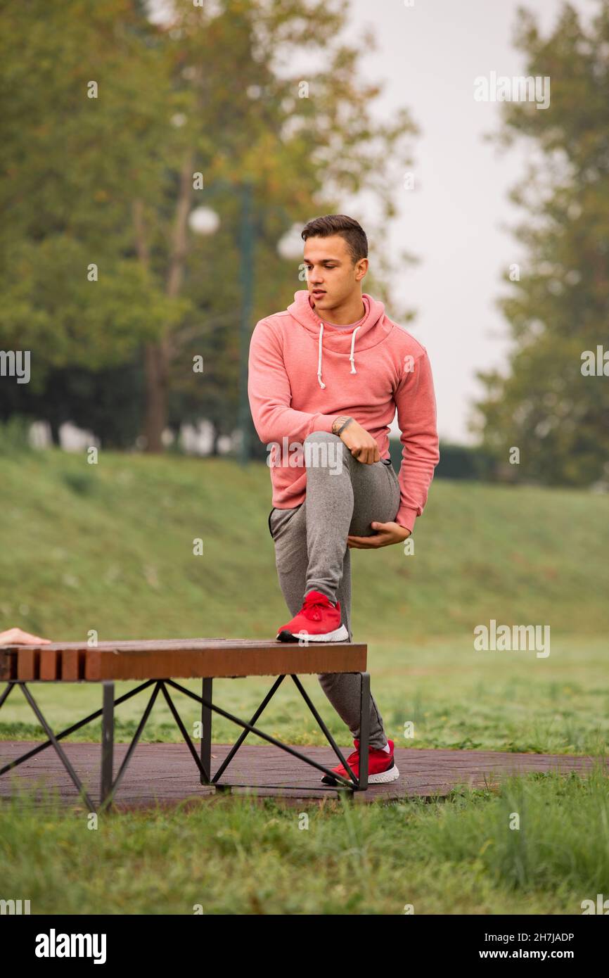 Attractive and handsome guy is stretching alone on the bench Stock ...
