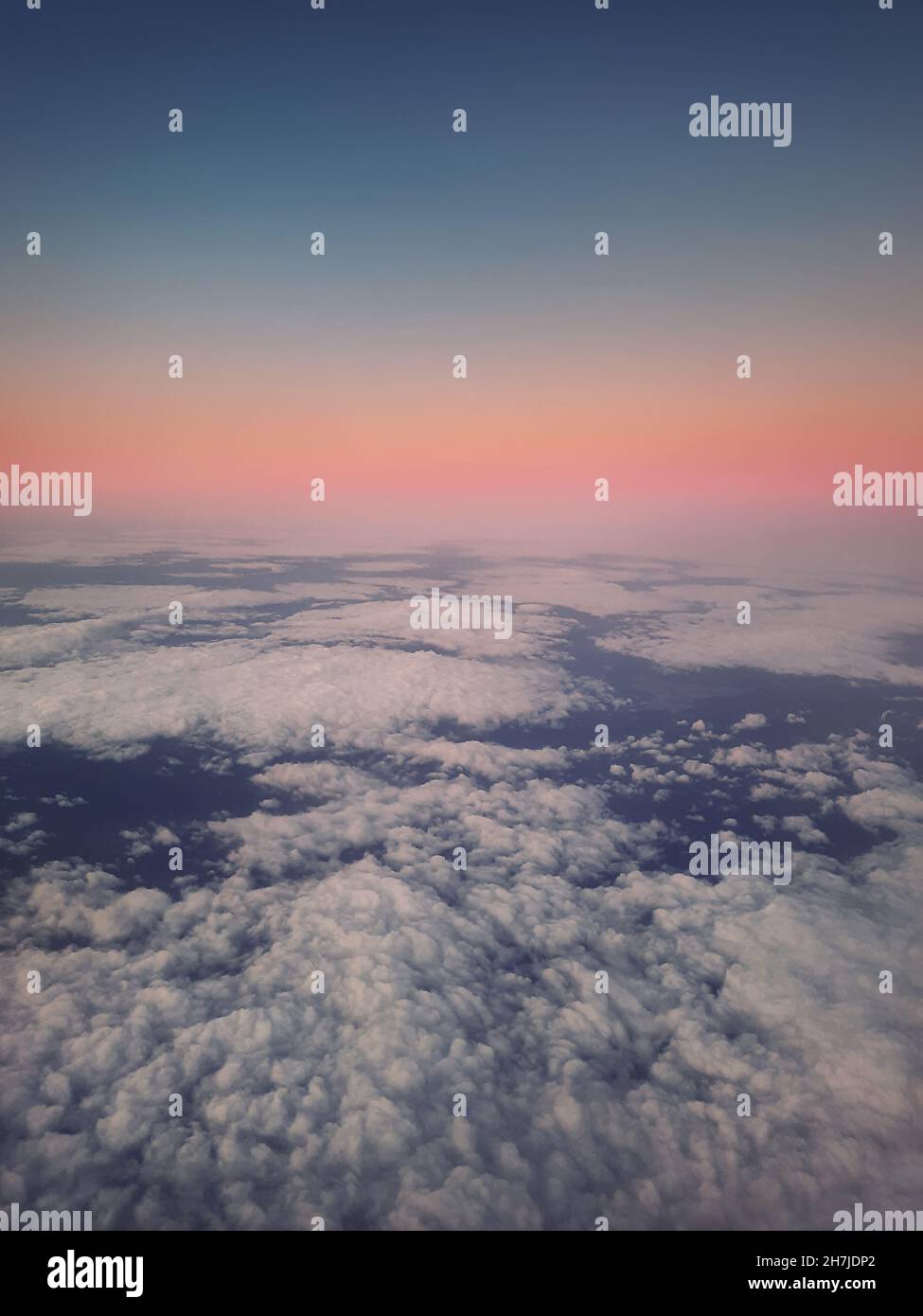 Sunset cloudscape, aerial view out of the plane window above the fluffy ...