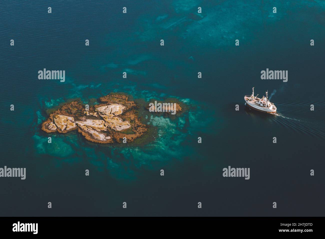 Island in blue sea and ship sailing aerial view drone scenery from ...