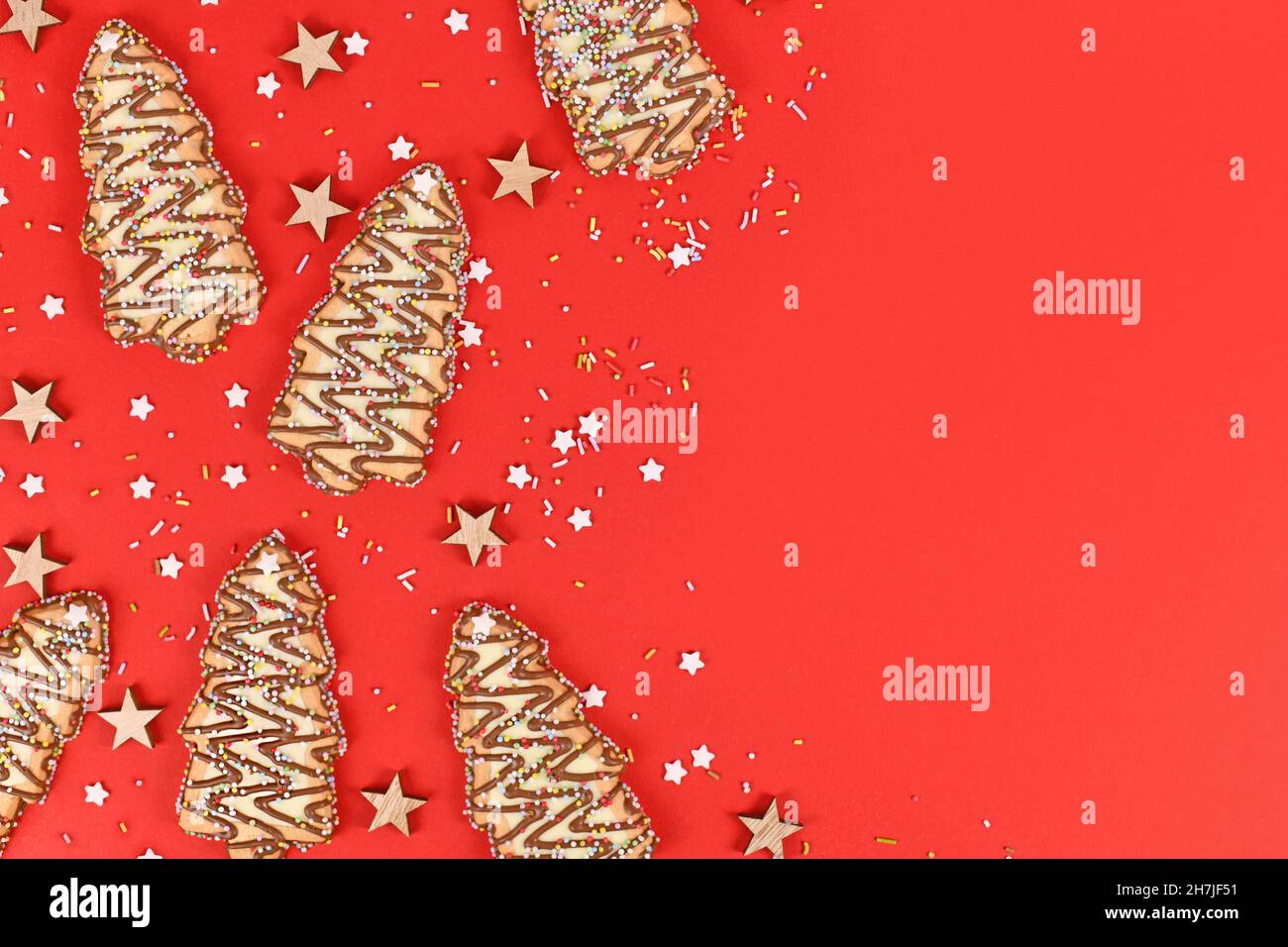 Christmas tree shaped cookies with sugar sprinkles on red background ...