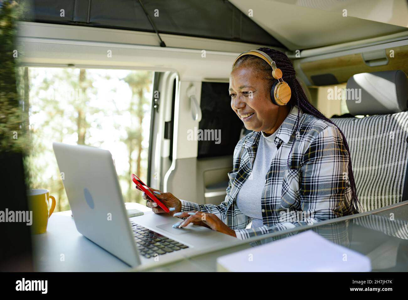 Happy black woman working remotely in caravan Stock Photo - Alamy