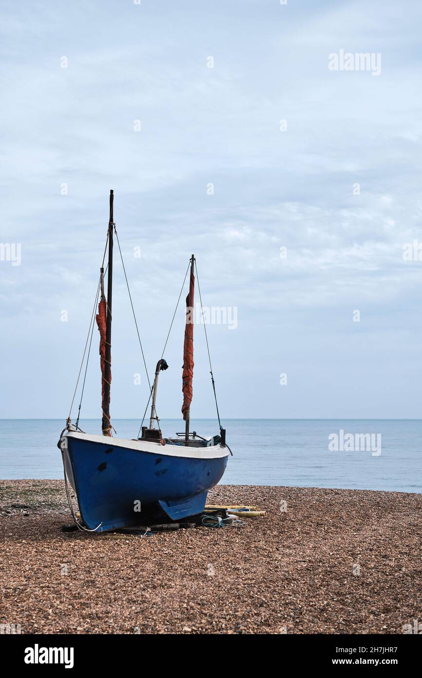 A traditional fishing boat sits on the pebbled sea shore of Rock A Nore ...