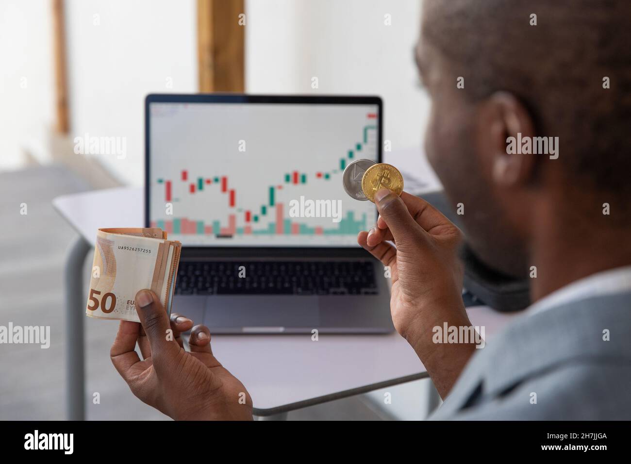 An investor holds cryptocurrencies and cash in hand and analyzes a ...