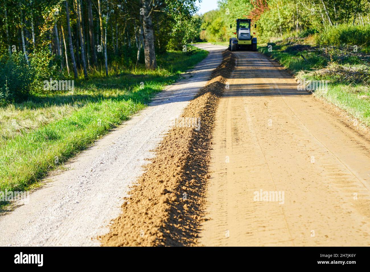 The grader is working on leveling gravel on a gravel road in a rural ...