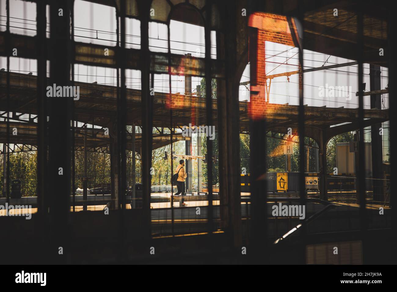 Person walking through a train bus station. Reflections on window ...