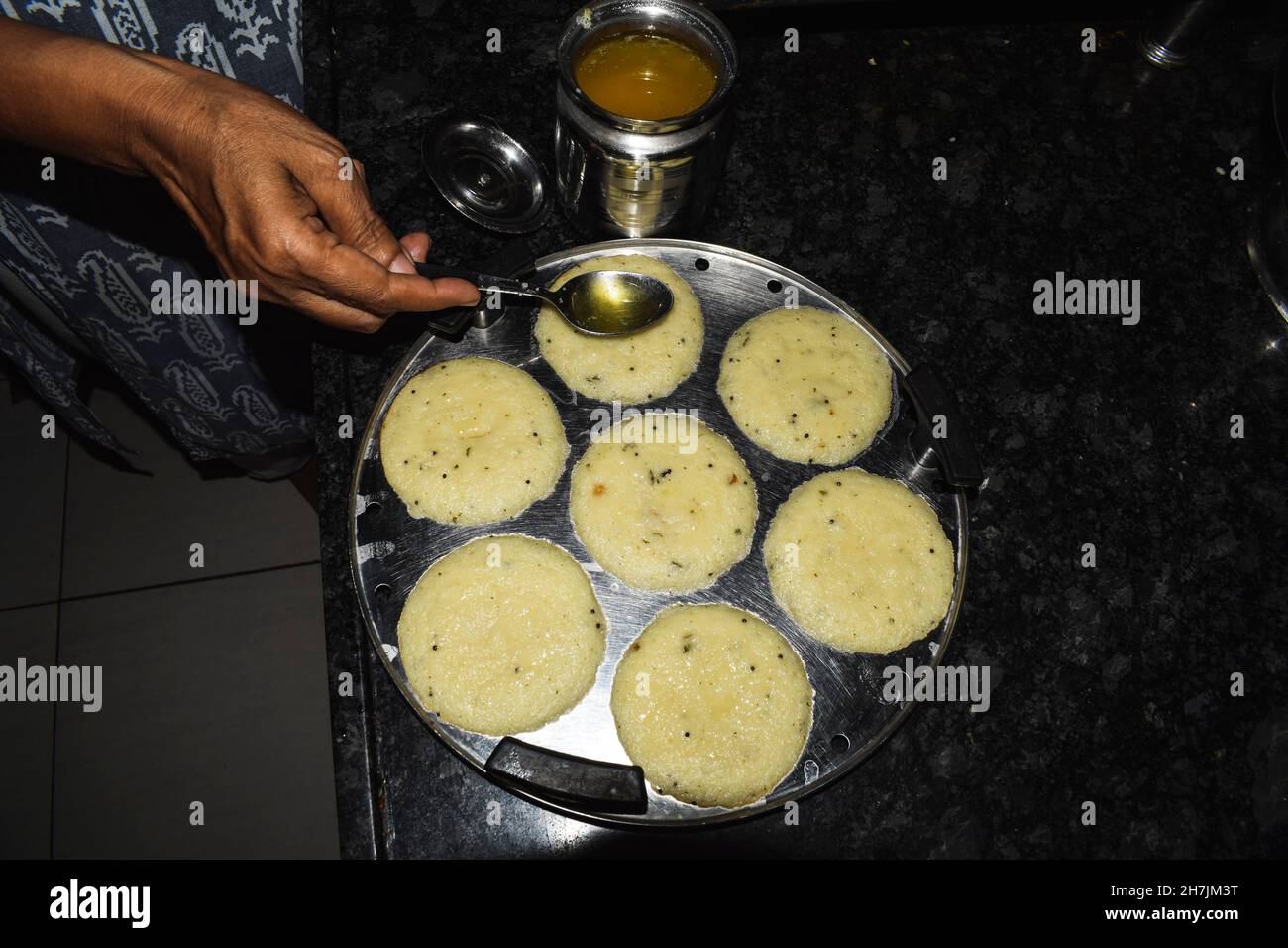 Woman hand cooking making popular south Indian steamed dish rava idli ...