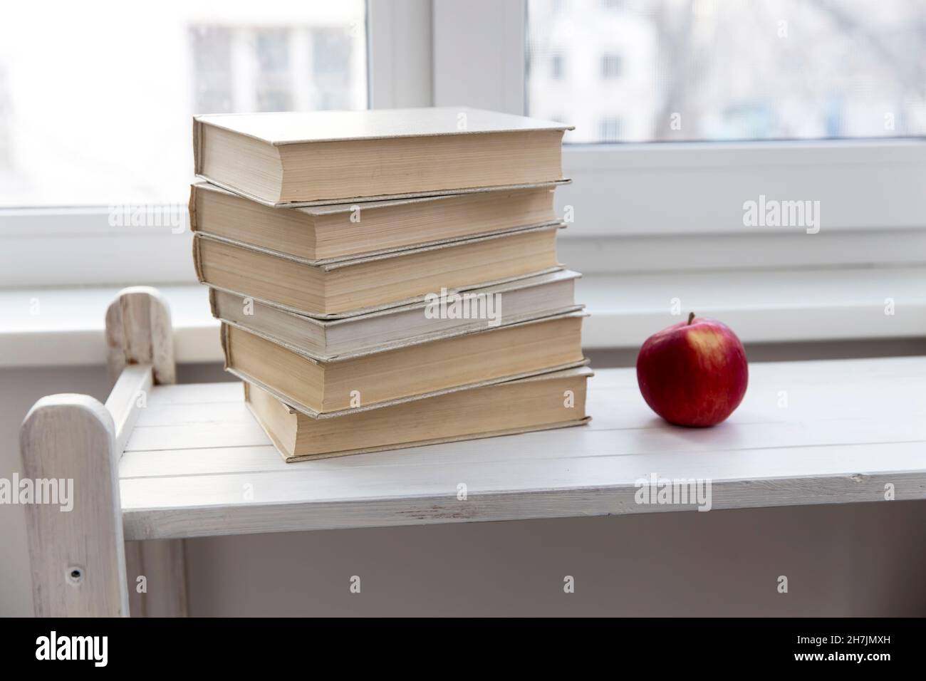 A stack of white-bound books is on the table against the background of ...