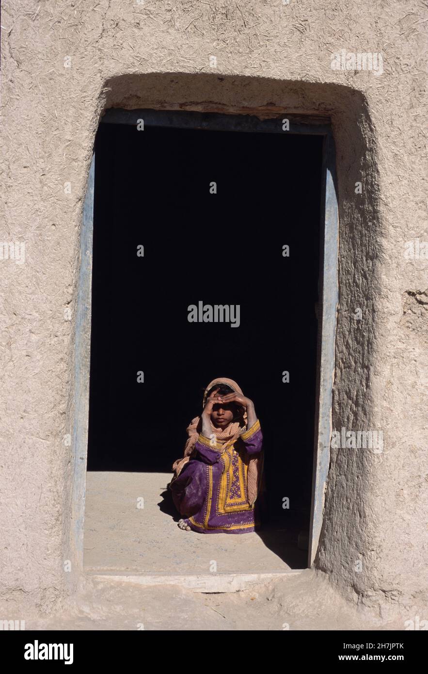 A Baluch girl sits at the doorstep of their mud home, at the village of ...