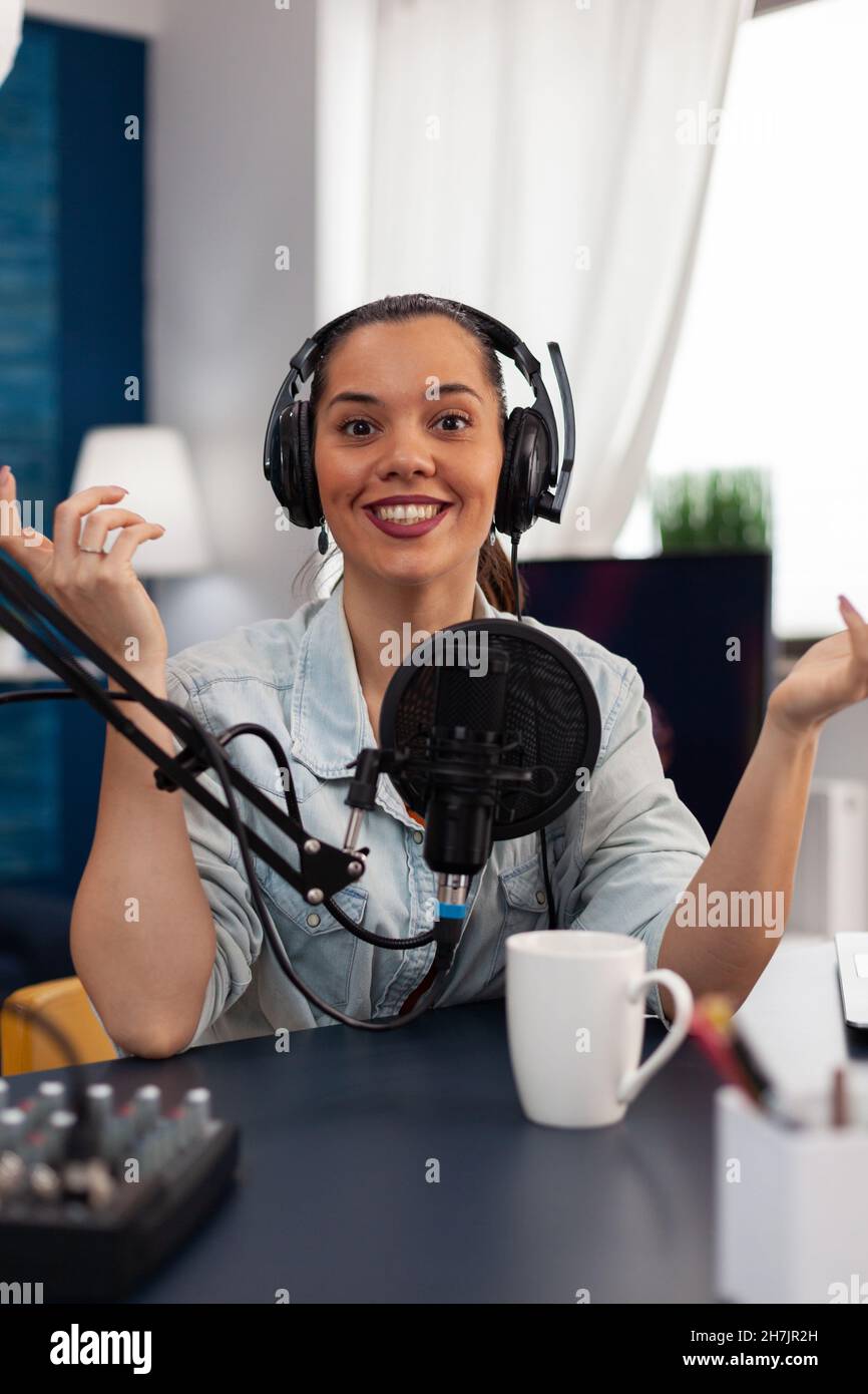 Portrait of smiling presenter streaming podcast using microphone ...