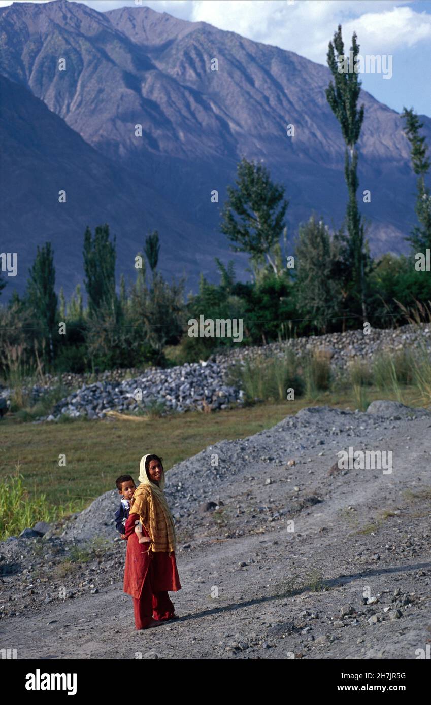 A woman carries her child on her back, near a village in Gilgit, in the ...