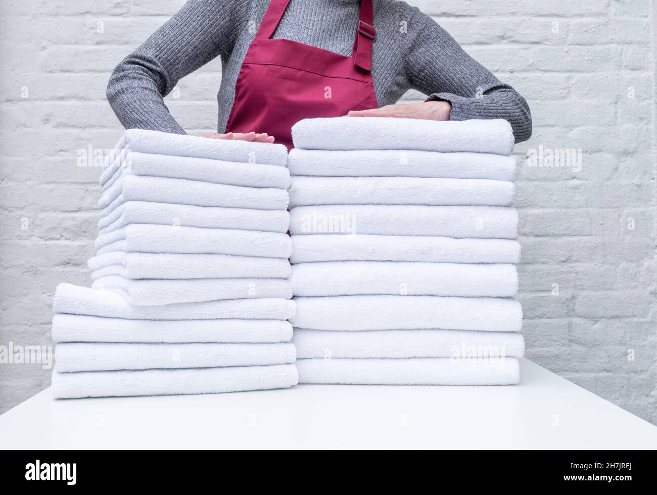 Worker hands hold a lot of white towels in laundry or hotel on white ...