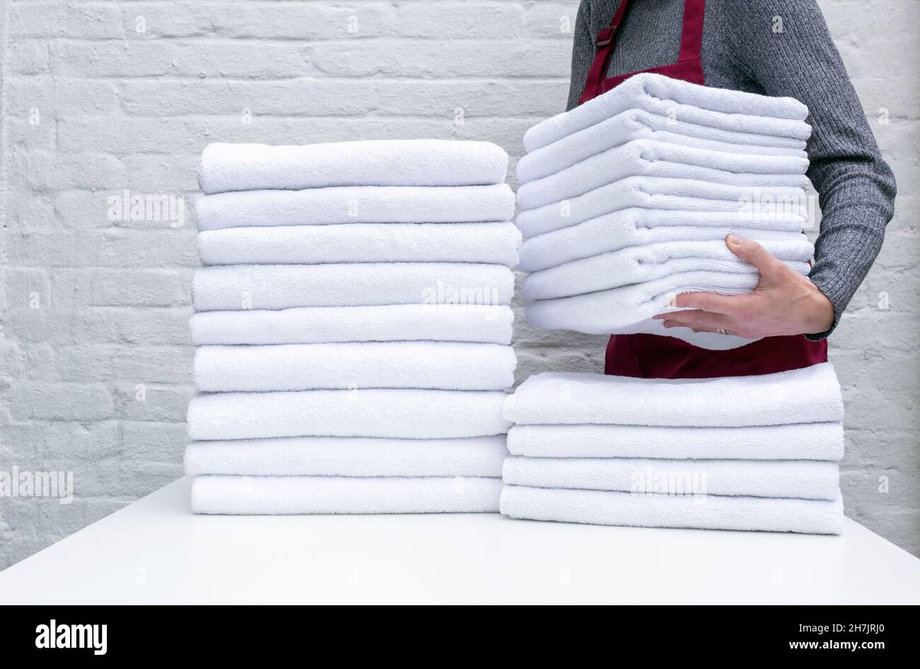 Worker hands hold a lot of white towels in laundry or hotel on white ...