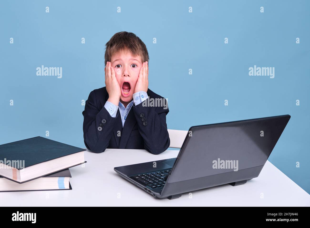 A scared boy in a school suit on distance learning, copy space on a ...
