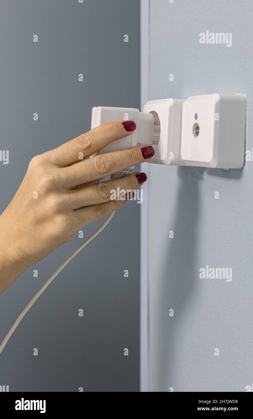 a female hand sticks the power supply into the socket. High quality ...