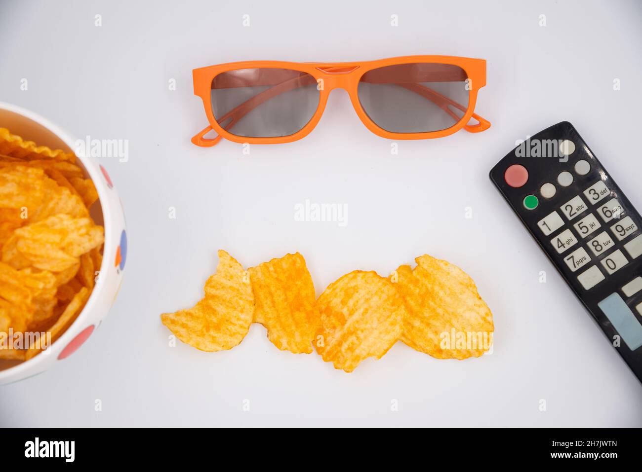 Top view of a table with a remote control, potato chips, and 3D glasses ...