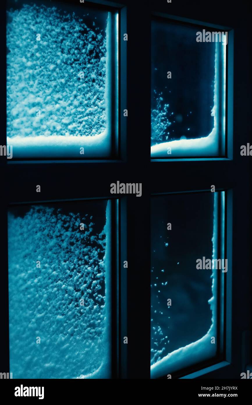 Snow-covered window frame on winter evening. Moon is shining through ...