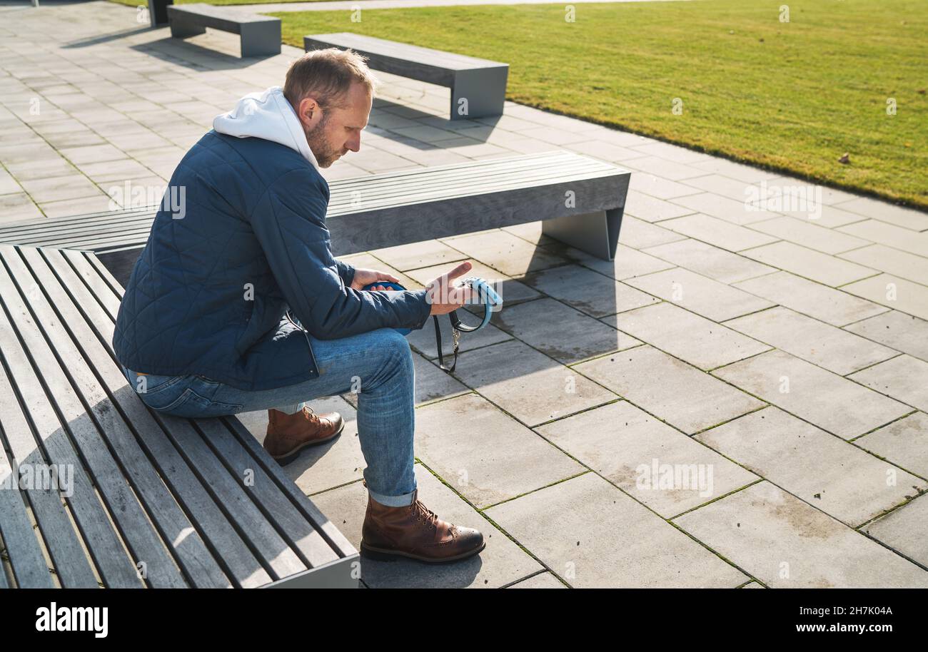 Broken with grief man as a dog owner is grieving sitting on a bench ...