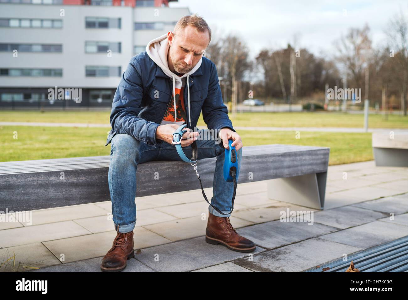 Broken with grief man as a dog owner is grieving sitting on a bench ...