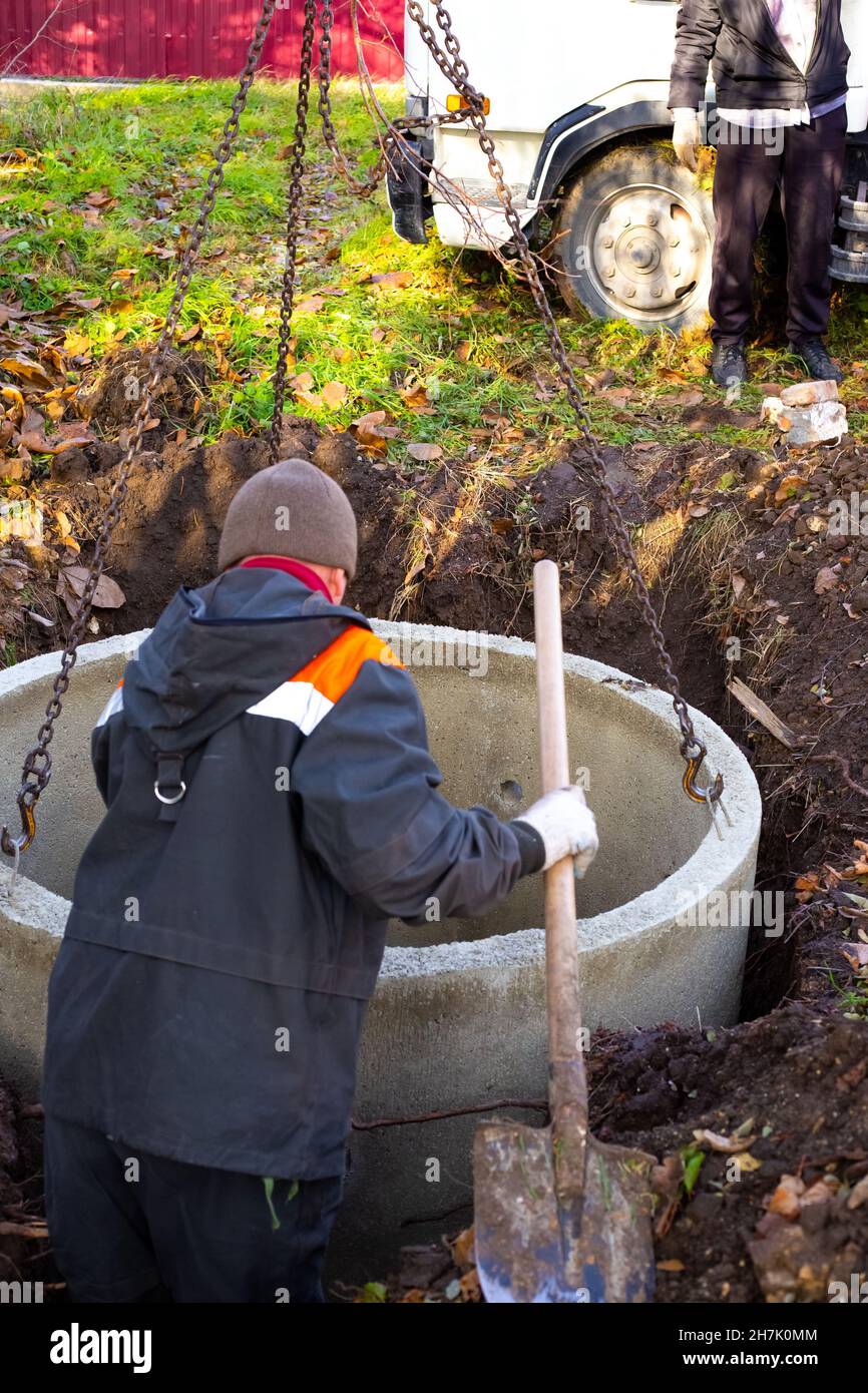 Construction of a septic tank for a rural house. A loader lowers ...