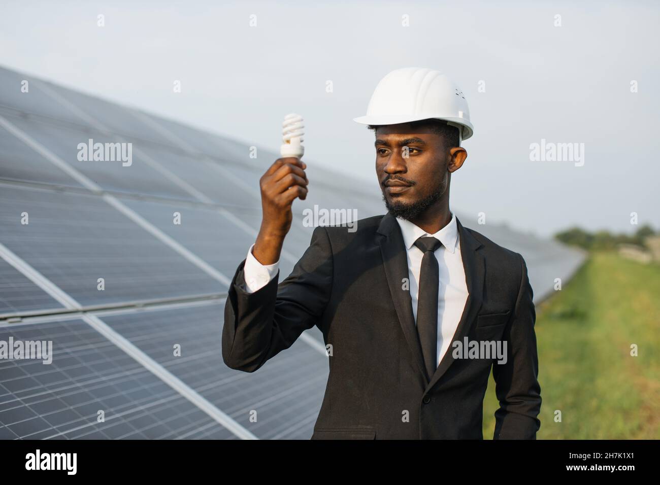 African american man with light bulb in hand standing on field with ...