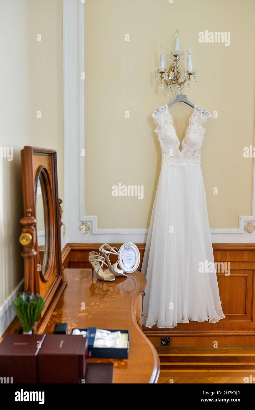 Bride room with a white wedding dress hanging from the lamp and shoes ...